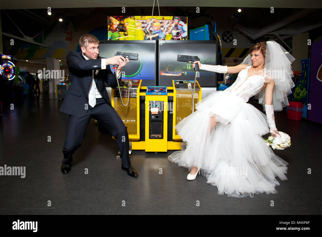 loving couple in their wedding clothes playing video games in the Mall ...