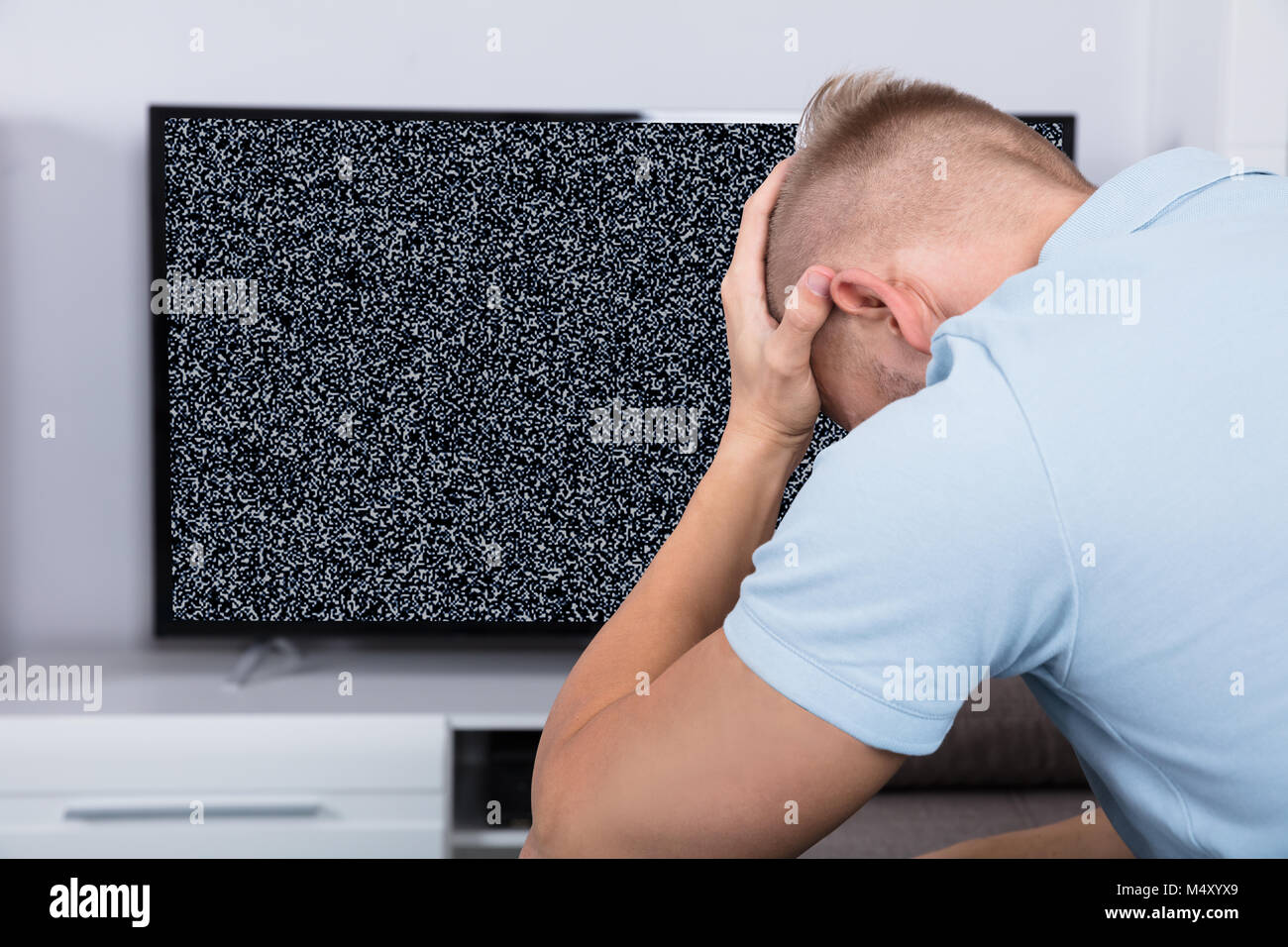 Frustrated Man Sitting On Sofa In Front Of Television With No Signal ...