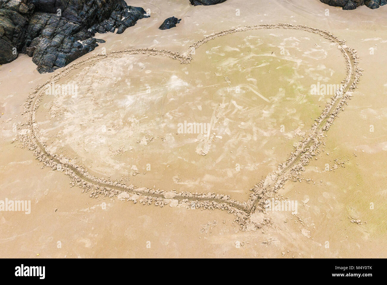 heart on a sand beach with rock as background Stock Photo - Alamy