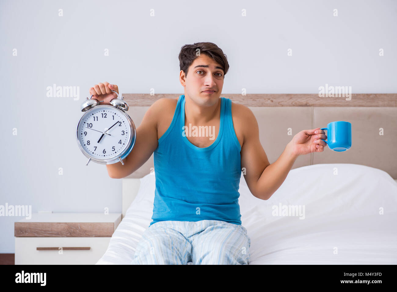 Young man waking up in bed Stock Photo - Alamy