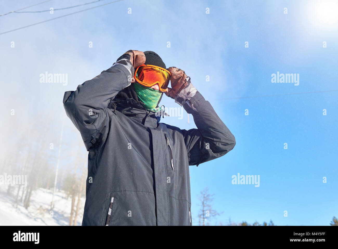 Low angle portrait of modern young man wearing snowboarding gear and ...