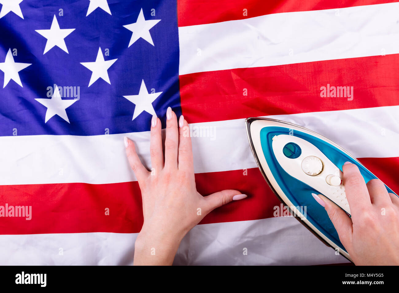 Woman hands pressing American Flag with an iron. Visual concept of ...