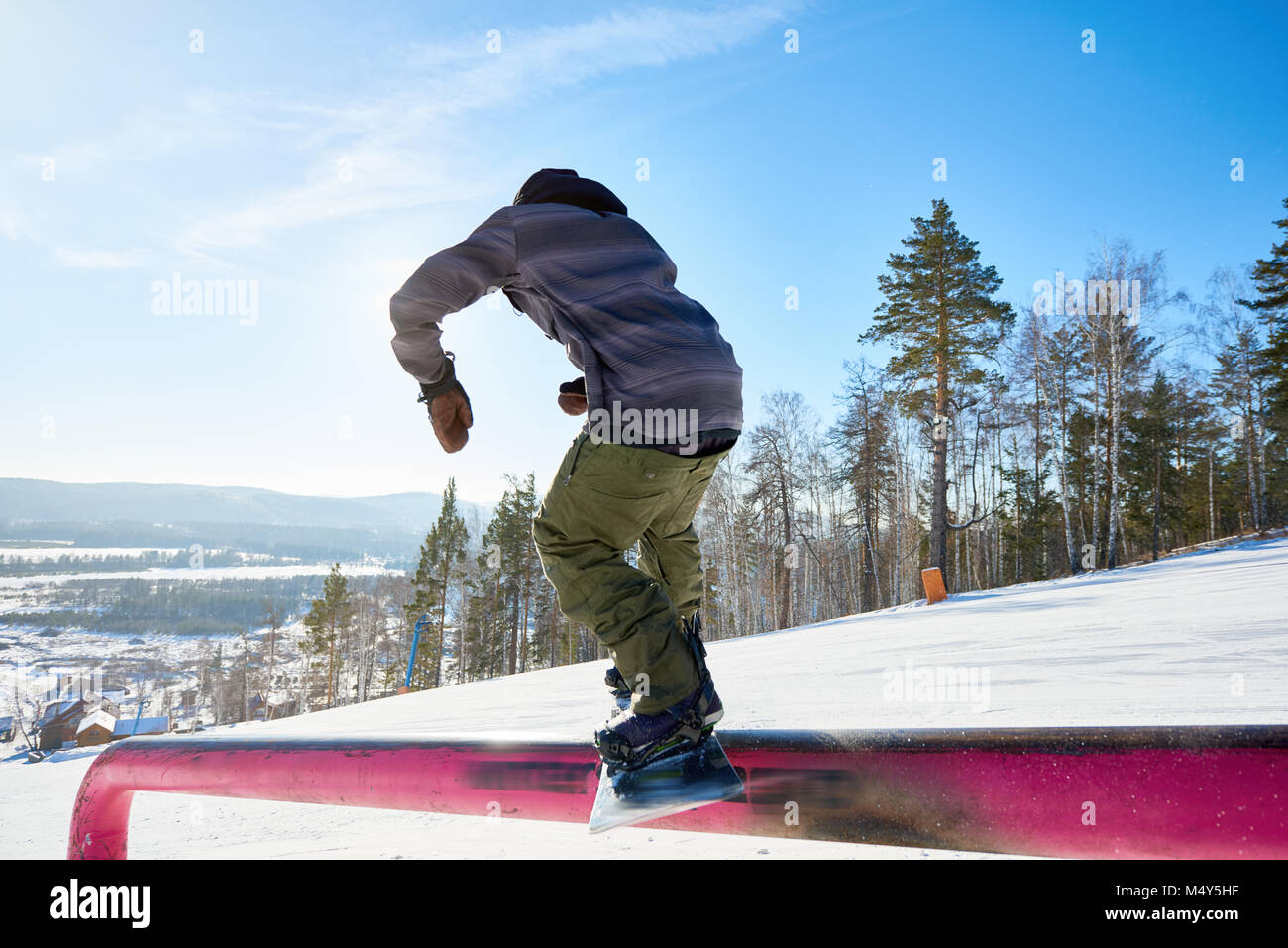 Back view portrait of young snowboarder performing stunt sliding down ...