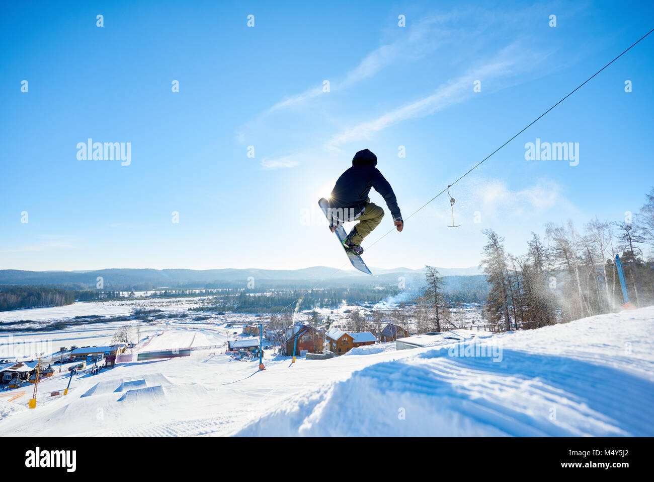 Back view action shot of young man performing snowboarding stunt ...
