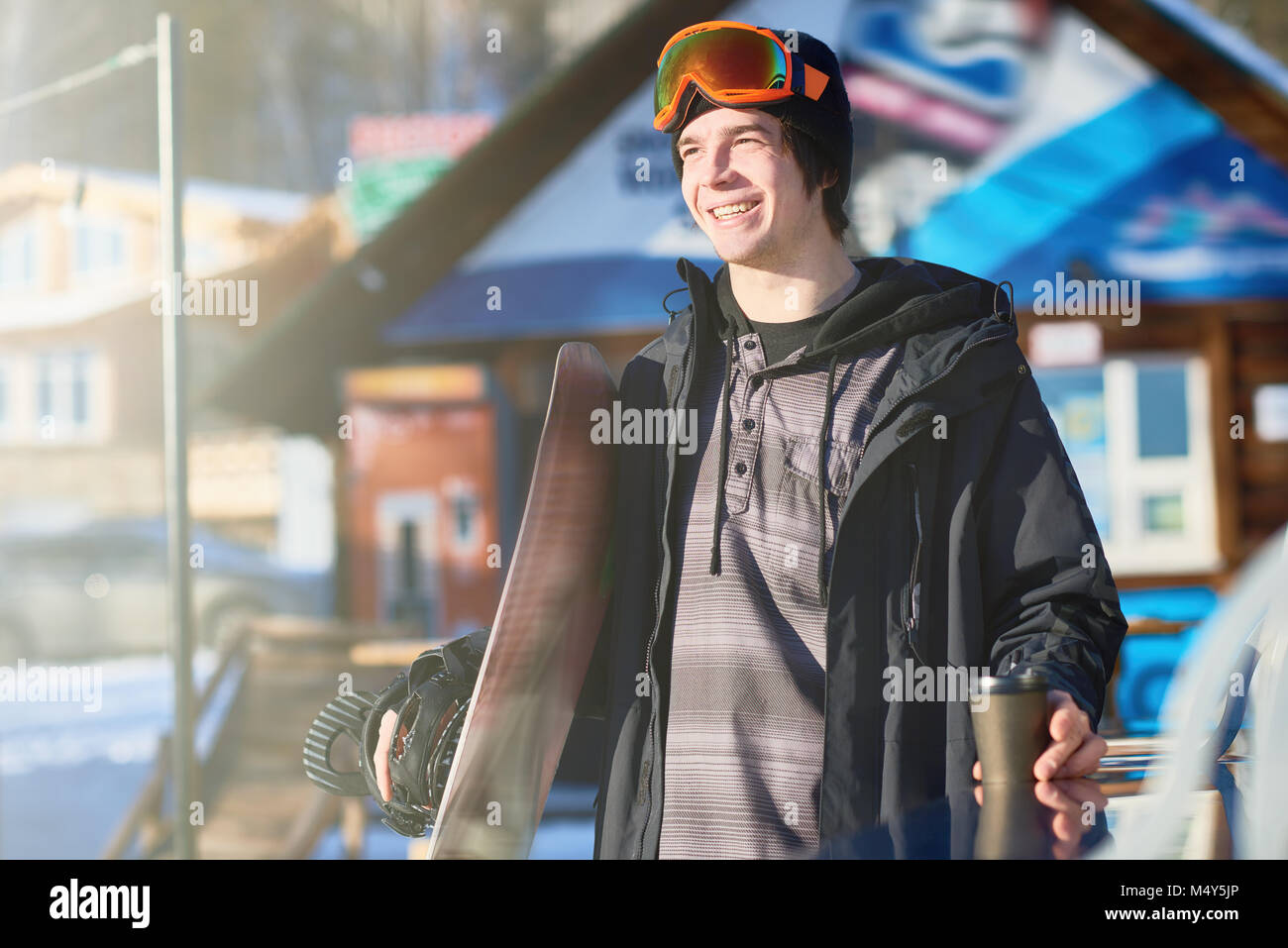 Portrait of modern young snowboarder smiling happily enjoying sunny ...