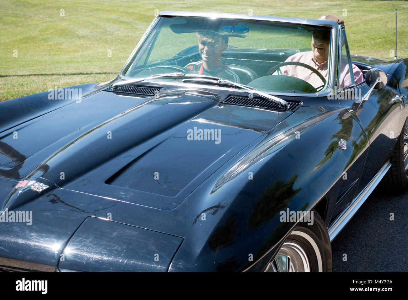 Happy young teen being chauffeured around by his uncle in a classic ...