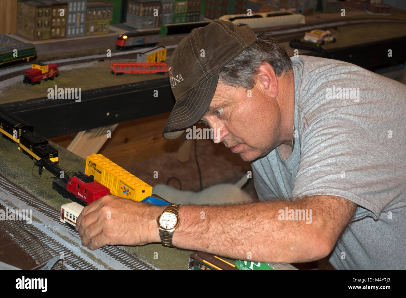 Retired man age 64 works on his model railroad hobby pastime ...