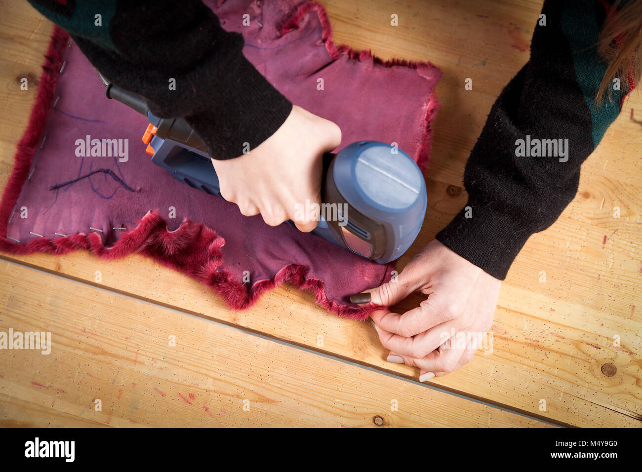 A close-up of a young furrier woman dries a special machine with ...