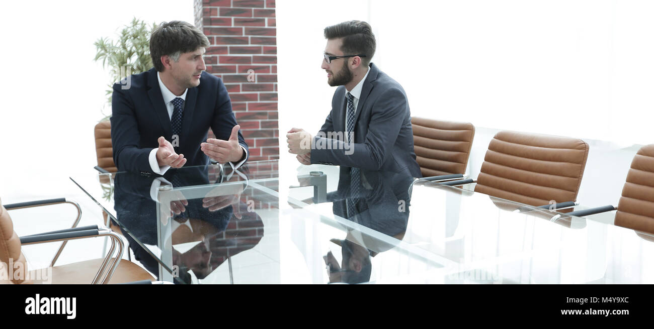 Two businessmen discussing tasks sitting at office table Stock Photo ...