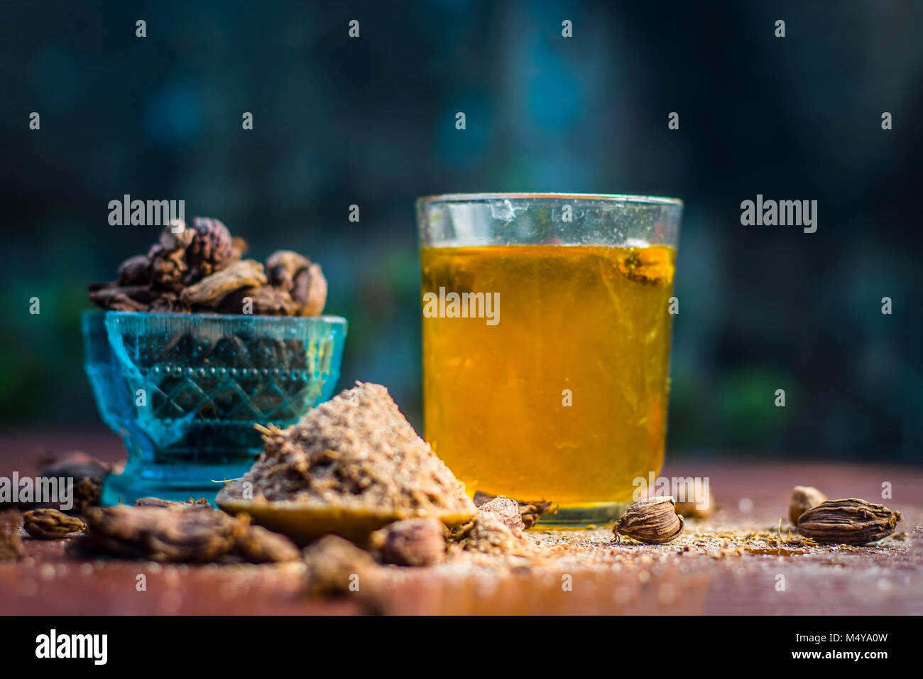 Close up of water of Black cardamom with its powder and raw whole black ...