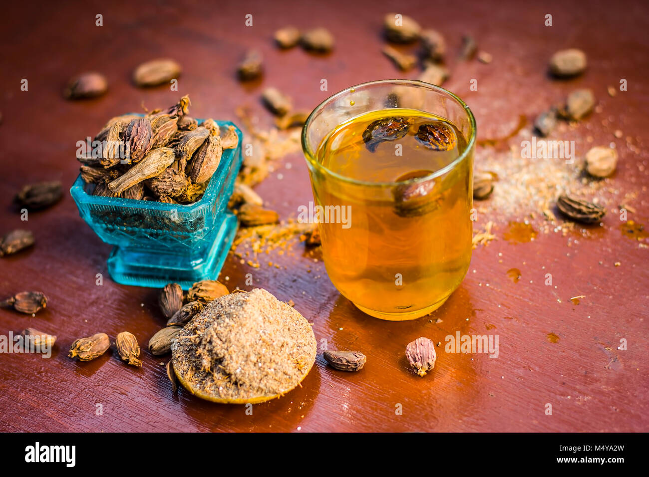 Close up of water of Black cardamom with its powder and raw whole black ...