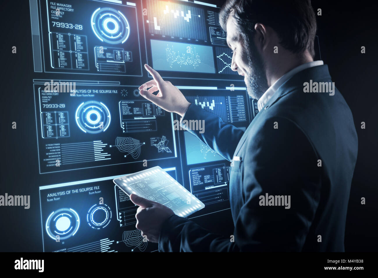 Young programmer looking at tablet while working with futuristic ...