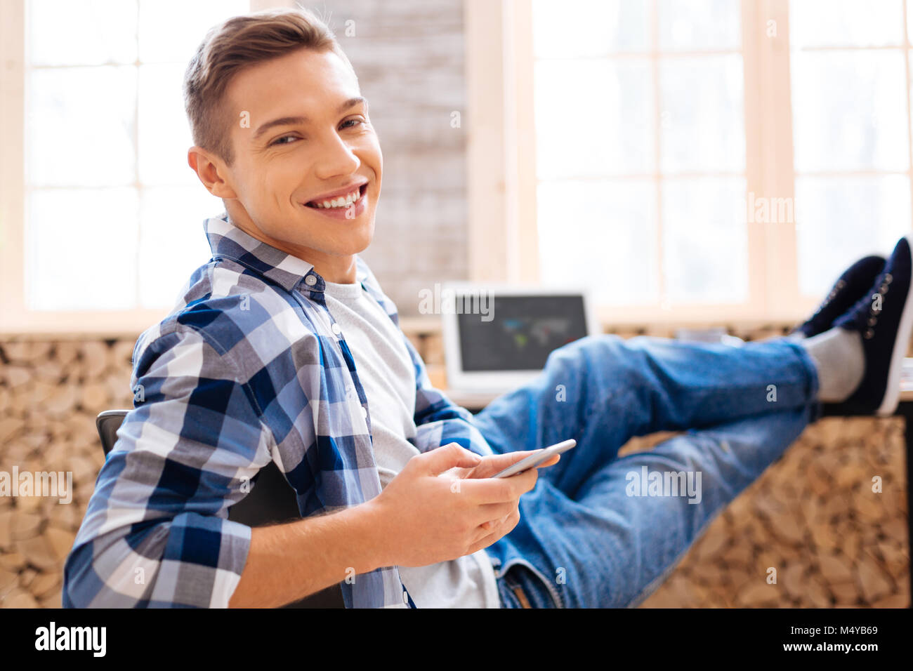 Content teenager sitting with his phone Stock Photo - Alamy