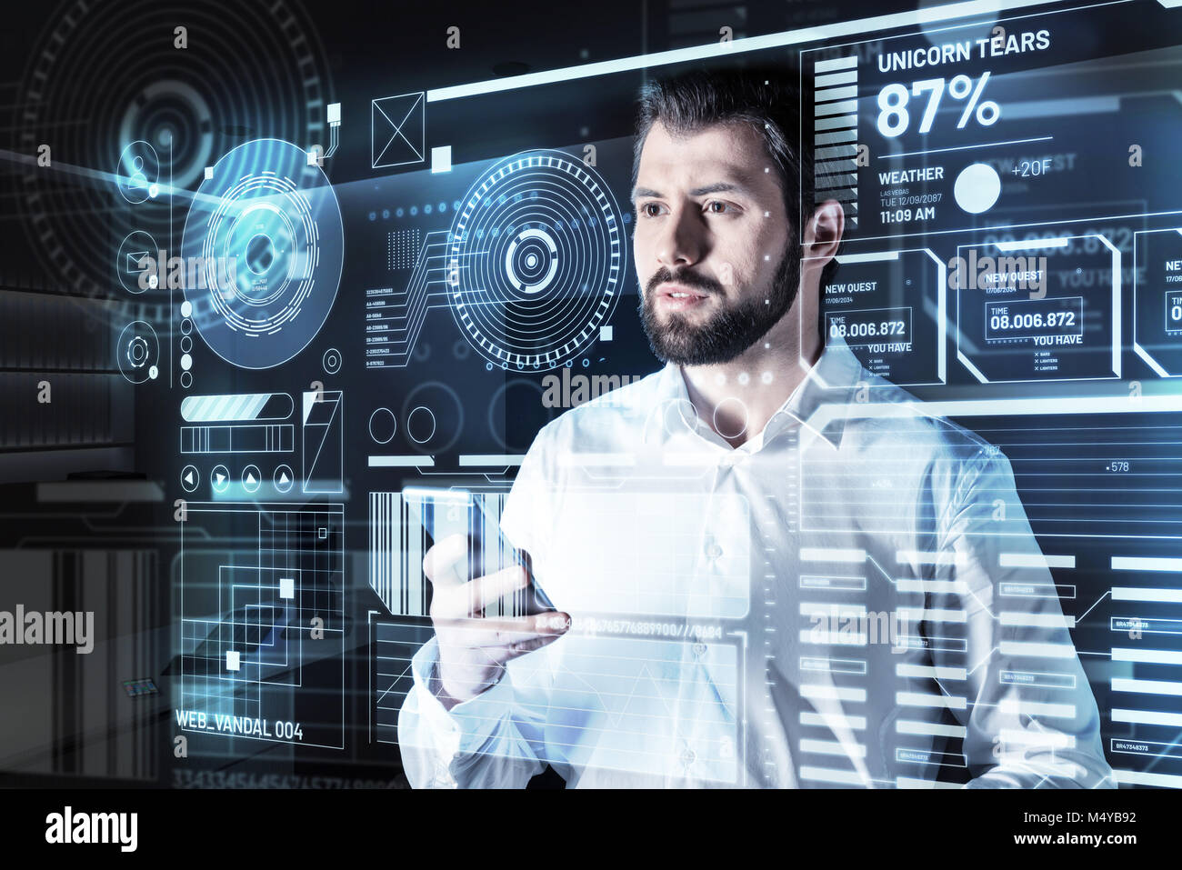 Thoughtful programmer looking at the screen while holding a smartphone Stock Photo - Alamy