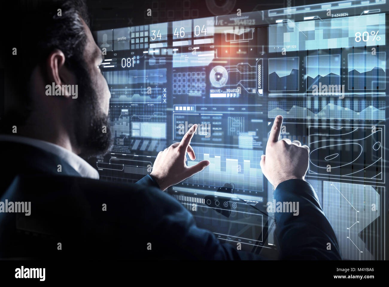 Bearded man touching icons on the transparent screen while working ...