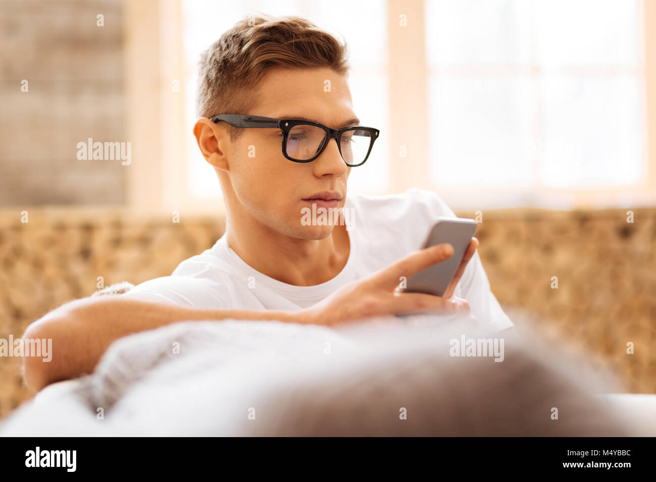 Unsmiling teenager using his phone Stock Photo - Alamy