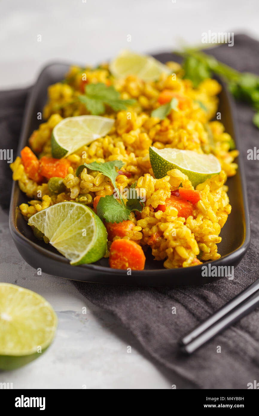 Vegetarian curry rice with vegetables in a black plate. Gray background ...
