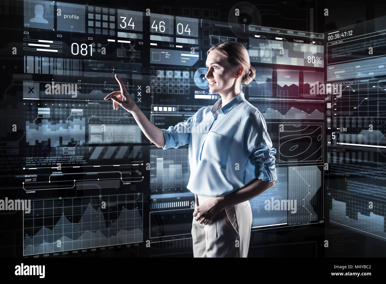 Cheerful woman smiling while pointing to the screen Stock Photo - Alamy