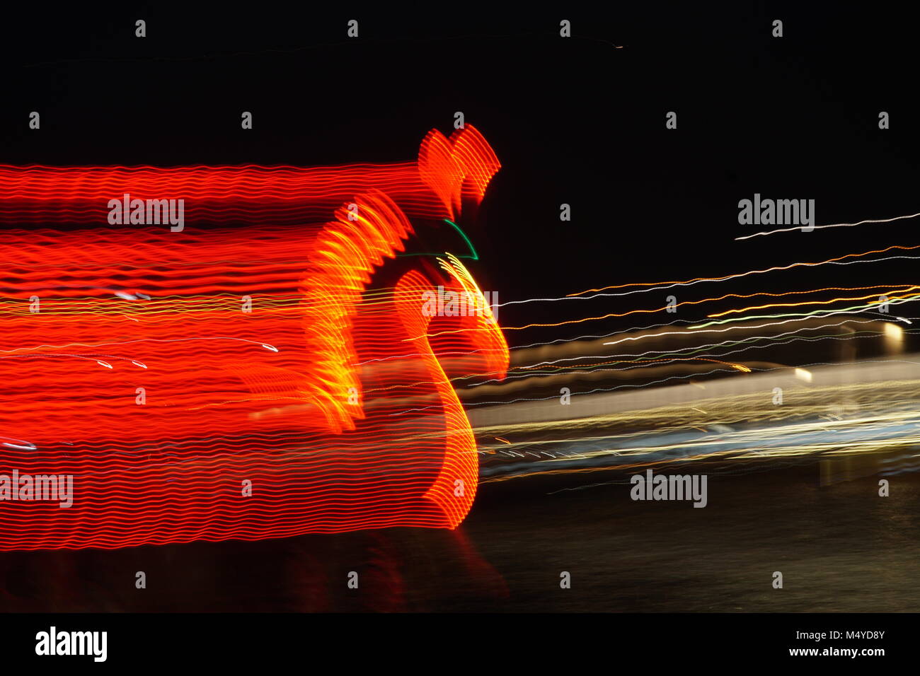 Abstract long exposured lines at night. The red shaped figure is looks ...