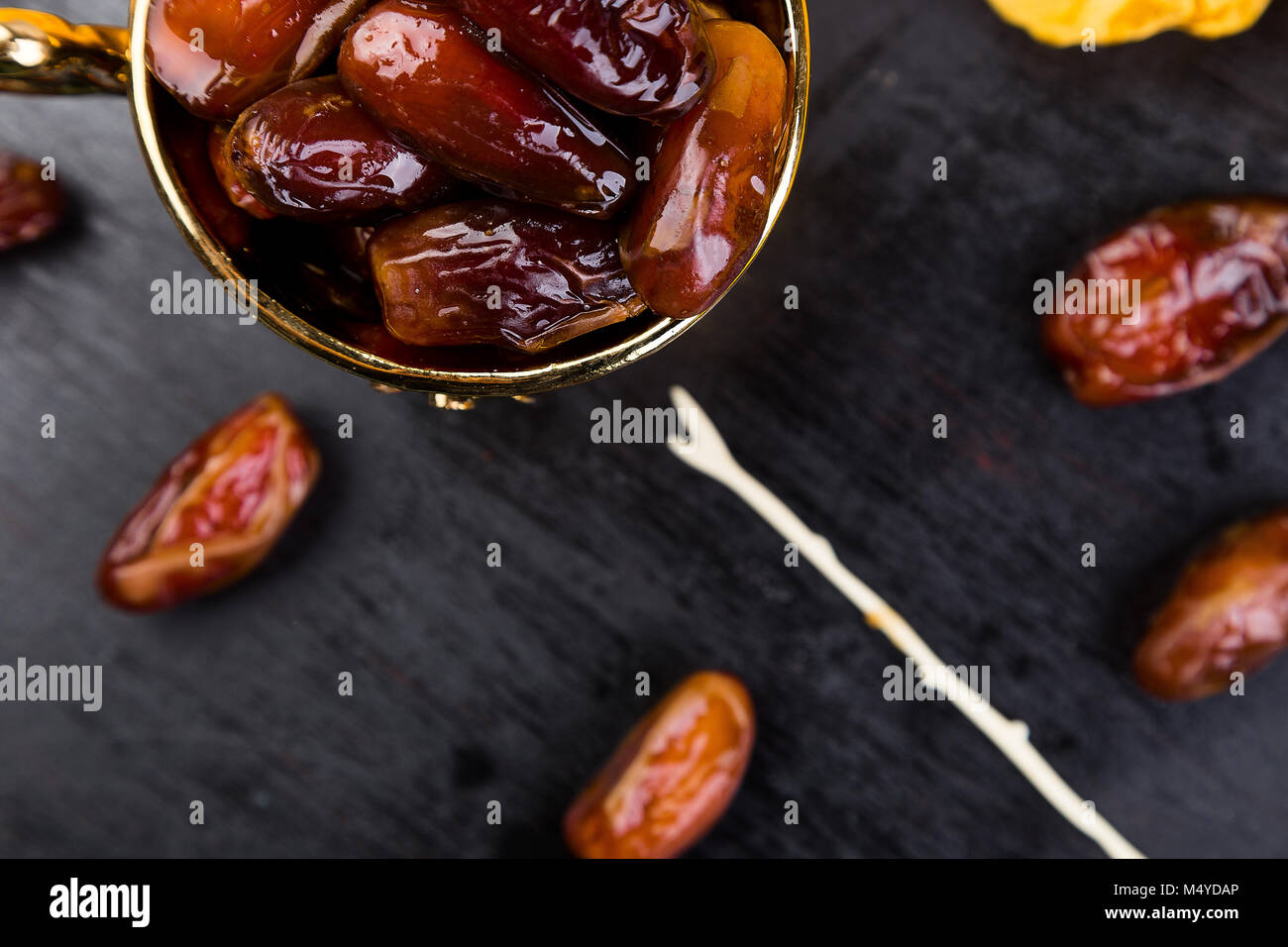Dry fruit dates in golden cup near slate black heart. Copy space Stock ...