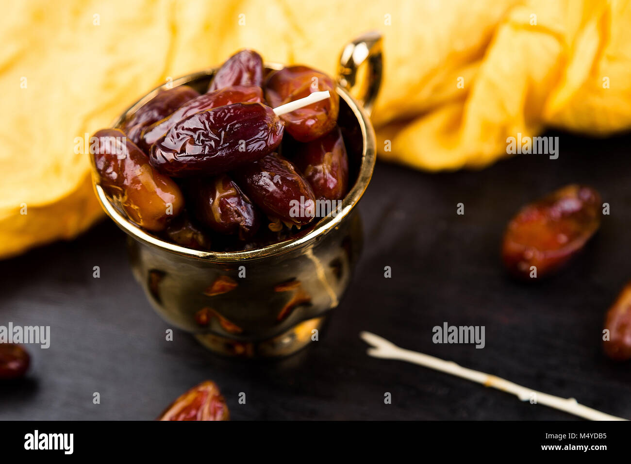 Dry fruit dates in golden cup near slate black heart. Copy space Stock ...