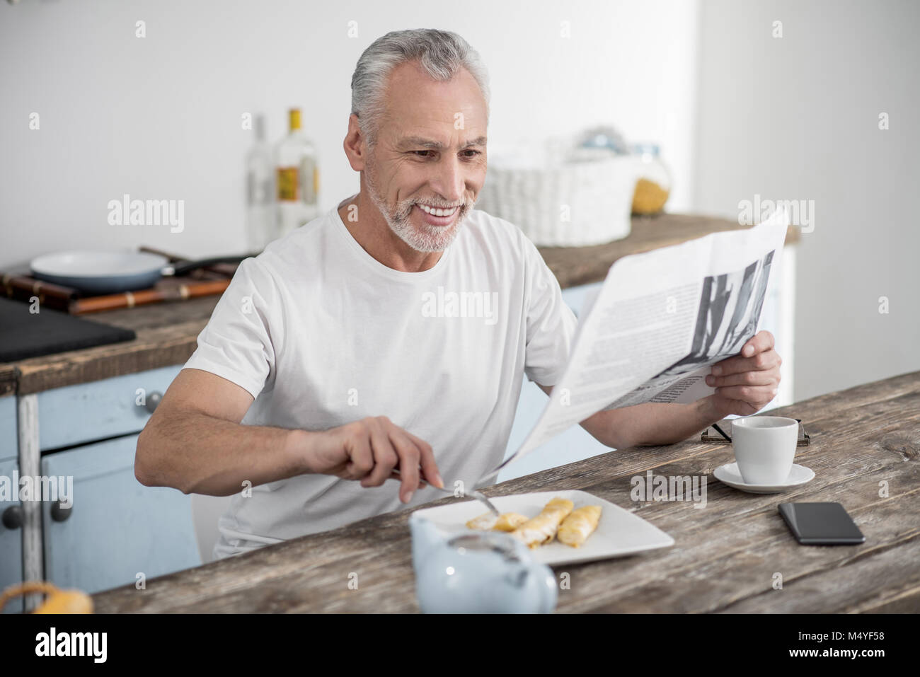 Cheerful male person reading fresh newspaper Stock Photo - Alamy