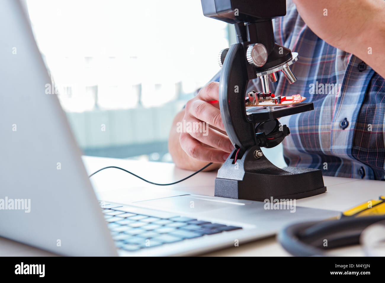 High precision engineering with man working with microscope Stock Photo ...