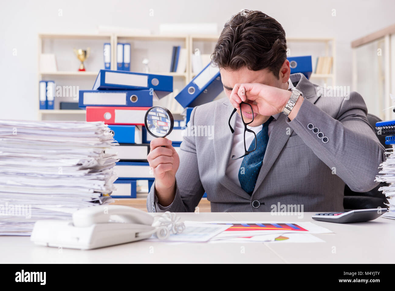 Male businessman with magnifying glass in office Stock Photo - Alamy