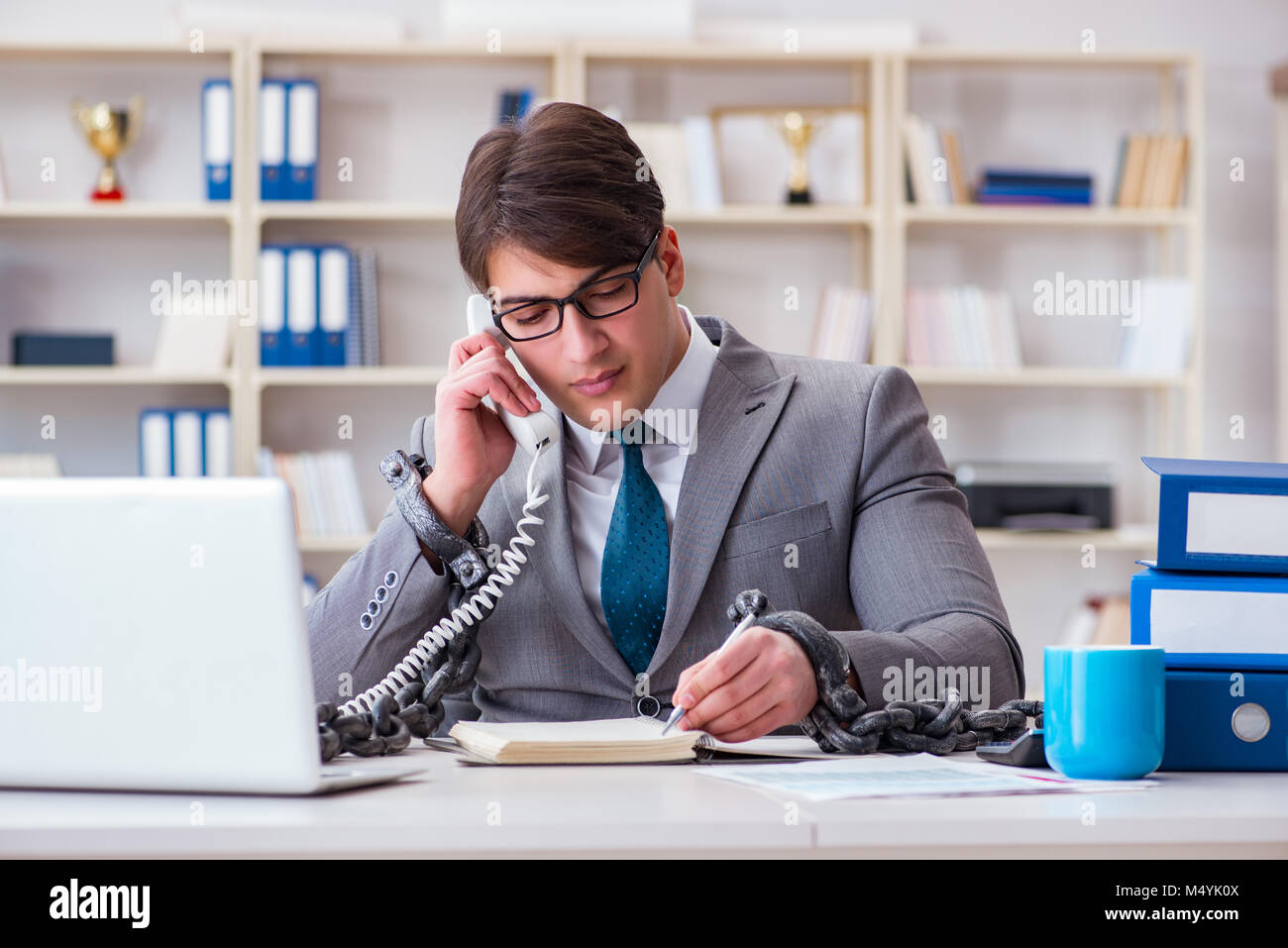 Businessman tied with chains to his work Stock Photo - Alamy