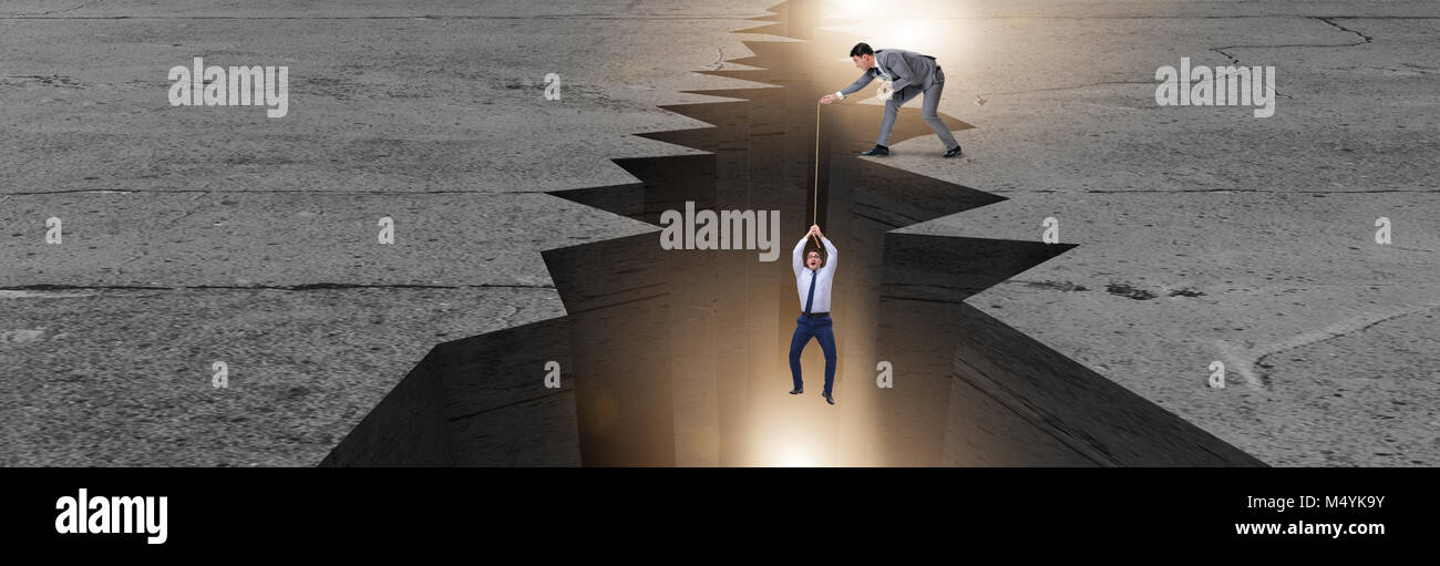 Man saving colleague pulling rope Stock Photo - Alamy