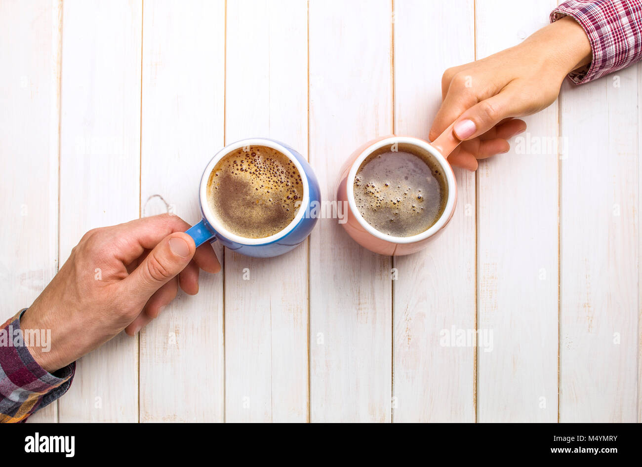 Man and woman holding cup of coffee on a wooden background. Two people ...