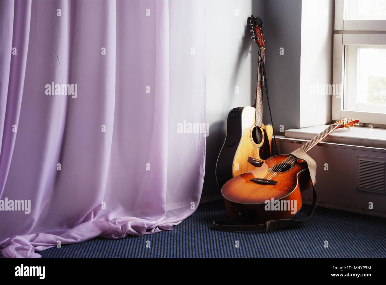 two acoustic guitar next the window Stock Photo - Alamy
