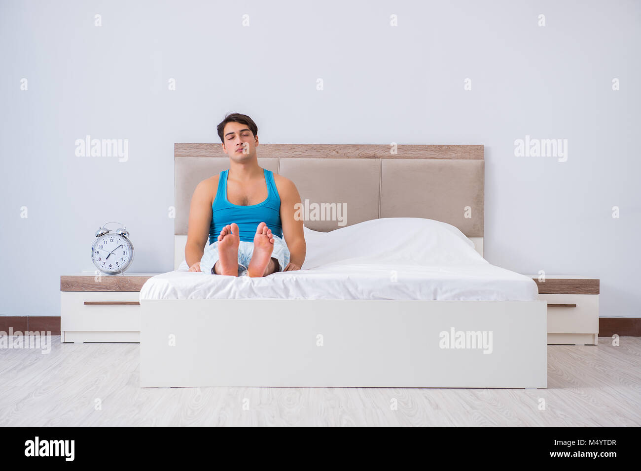 Young man waking up in bed Stock Photo - Alamy