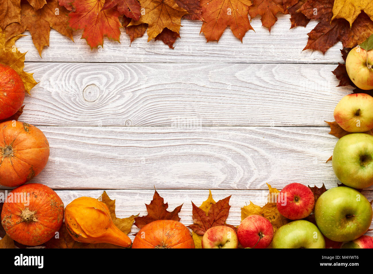 Autumn leaves, apples and pumpkins over wooden background Stock Photo ...