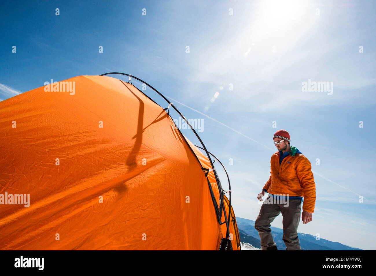 Man standing outside tent while camping in winter in White Mountains ...