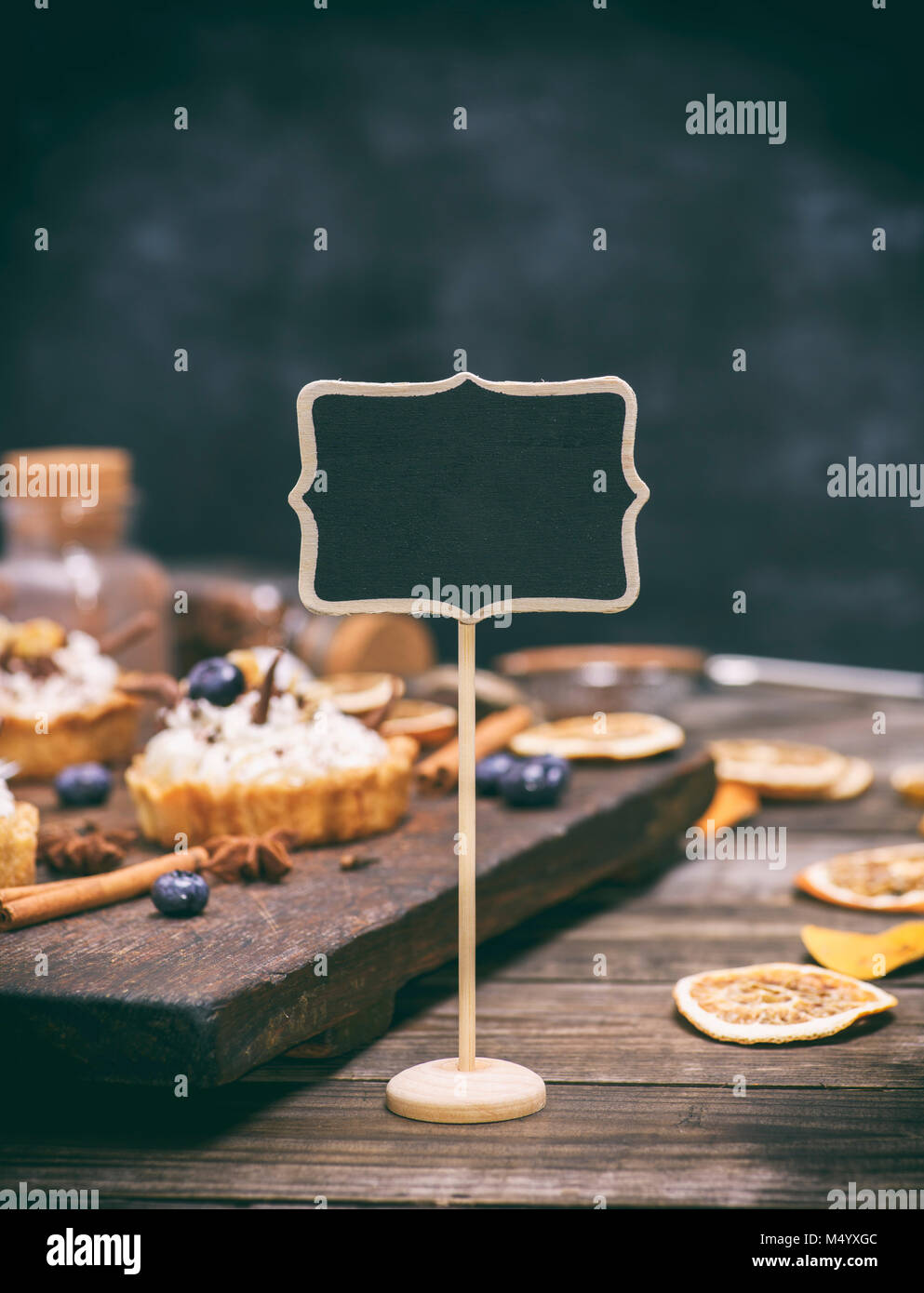 Empty wooden sign with a black surface on a table with cakes, vintage ...