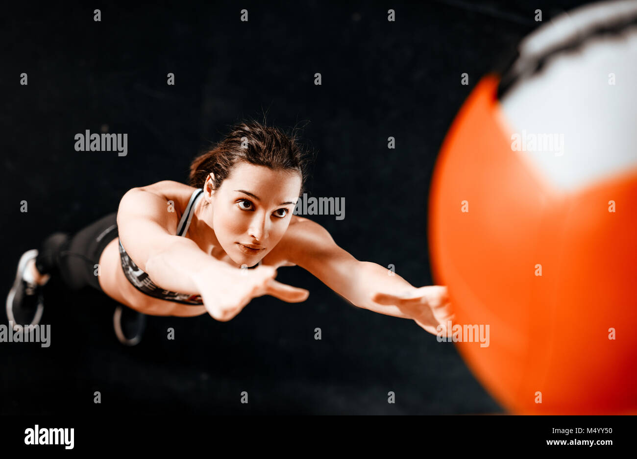 Attractive young muscular woman throwing a wall ball at the gym. Top ...