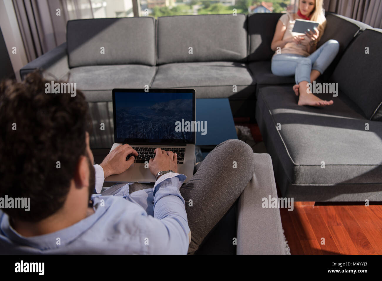 Young couple relaxing at home using tablet and laptop computers reading ...