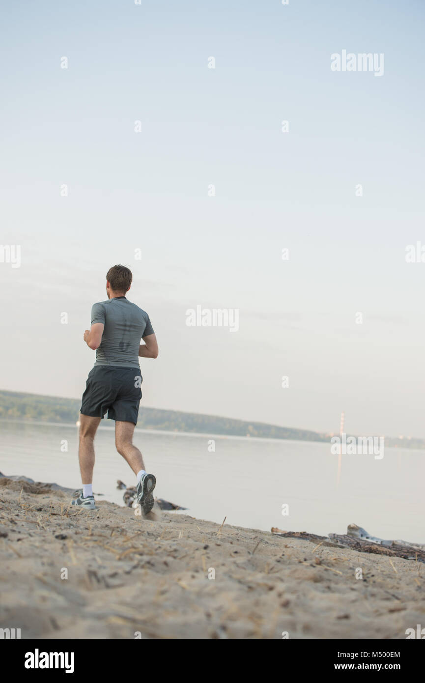 Male athlete/runner running on beach - jog workout well-being concept ...