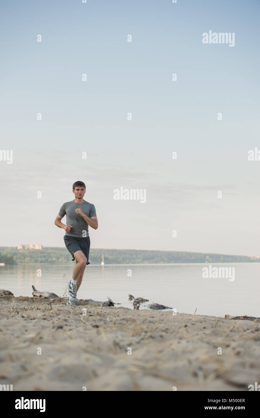 Male athlete/runner running on beach - jog workout well-being concept ...