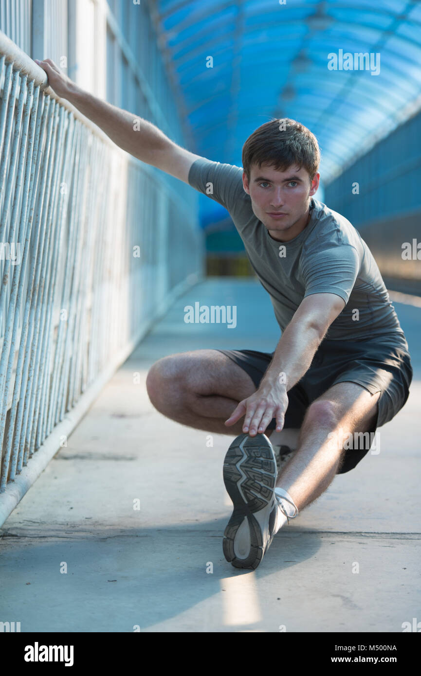 Attractive fit young man stretching before exercise, sunrise early ...