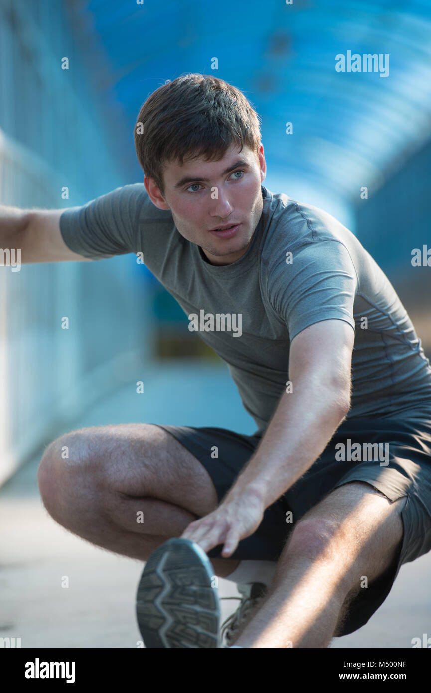 Attractive fit young man stretching before exercise, sunrise early ...
