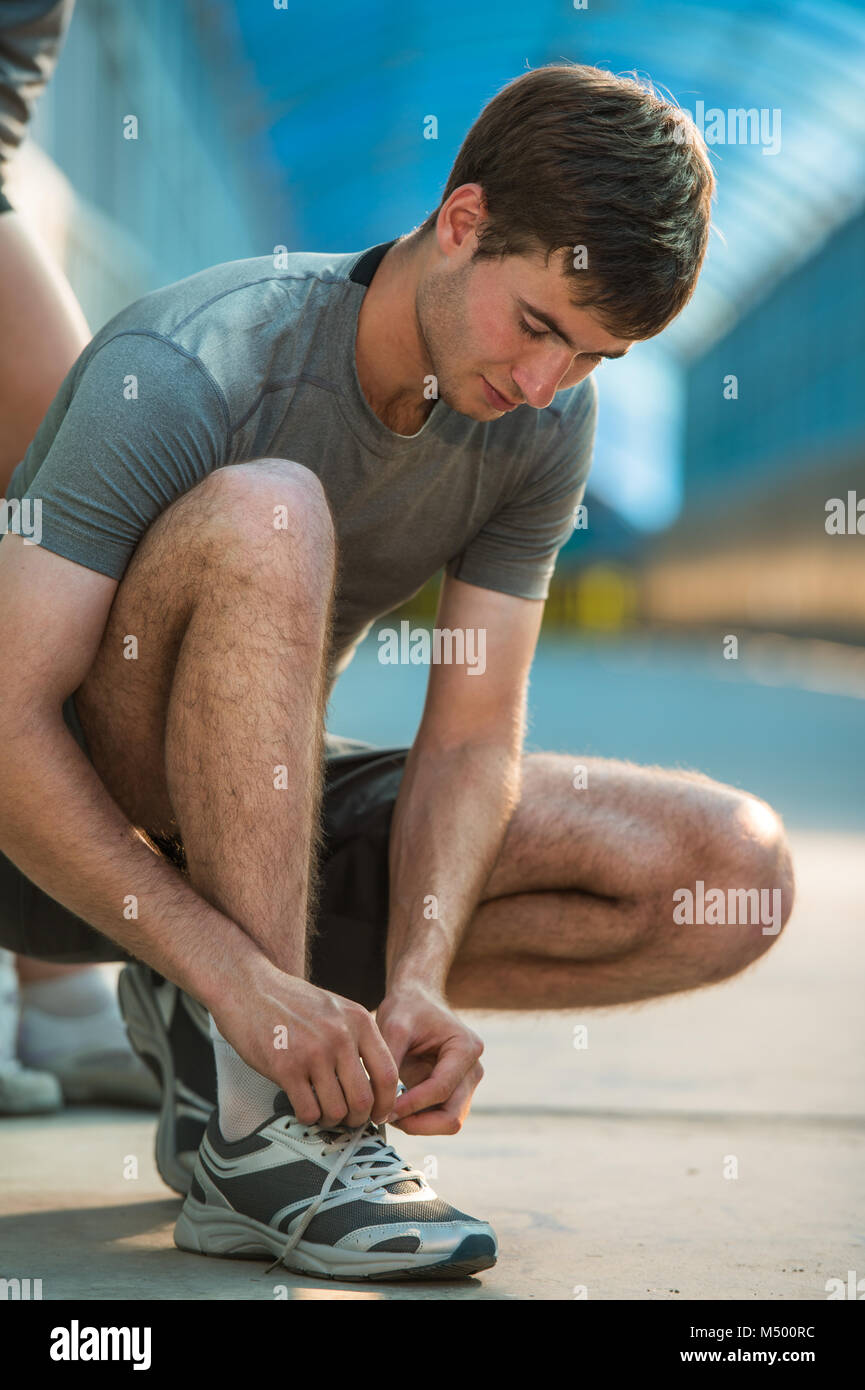 Handsome man lacing his shoes before running outdoors Stock Photo - Alamy