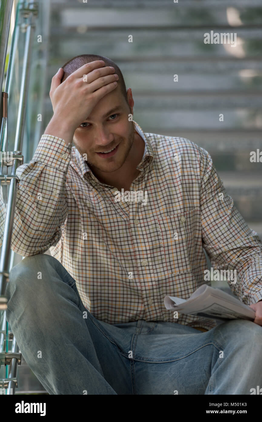 Handsome man reading a newspaper and thinking Stock Photo - Alamy