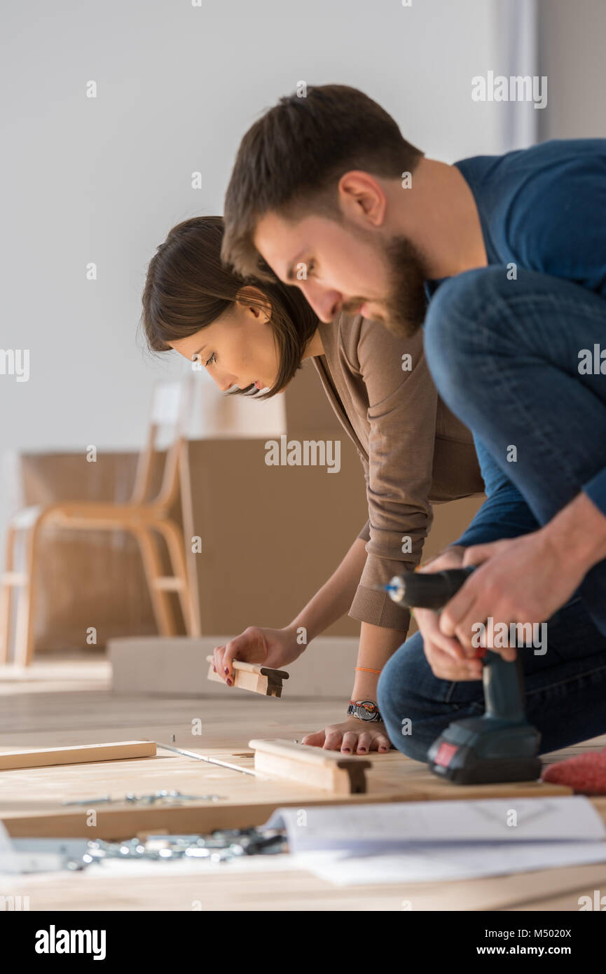 Happy young couple putting together self assembly furniture as they ...