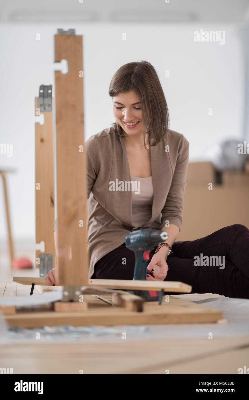 Young woman doing DIY repairs at home putting together self assembly ...