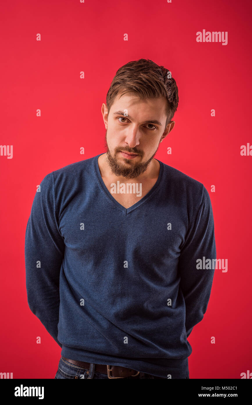 Serious man looking at camera standing against red background Stock ...