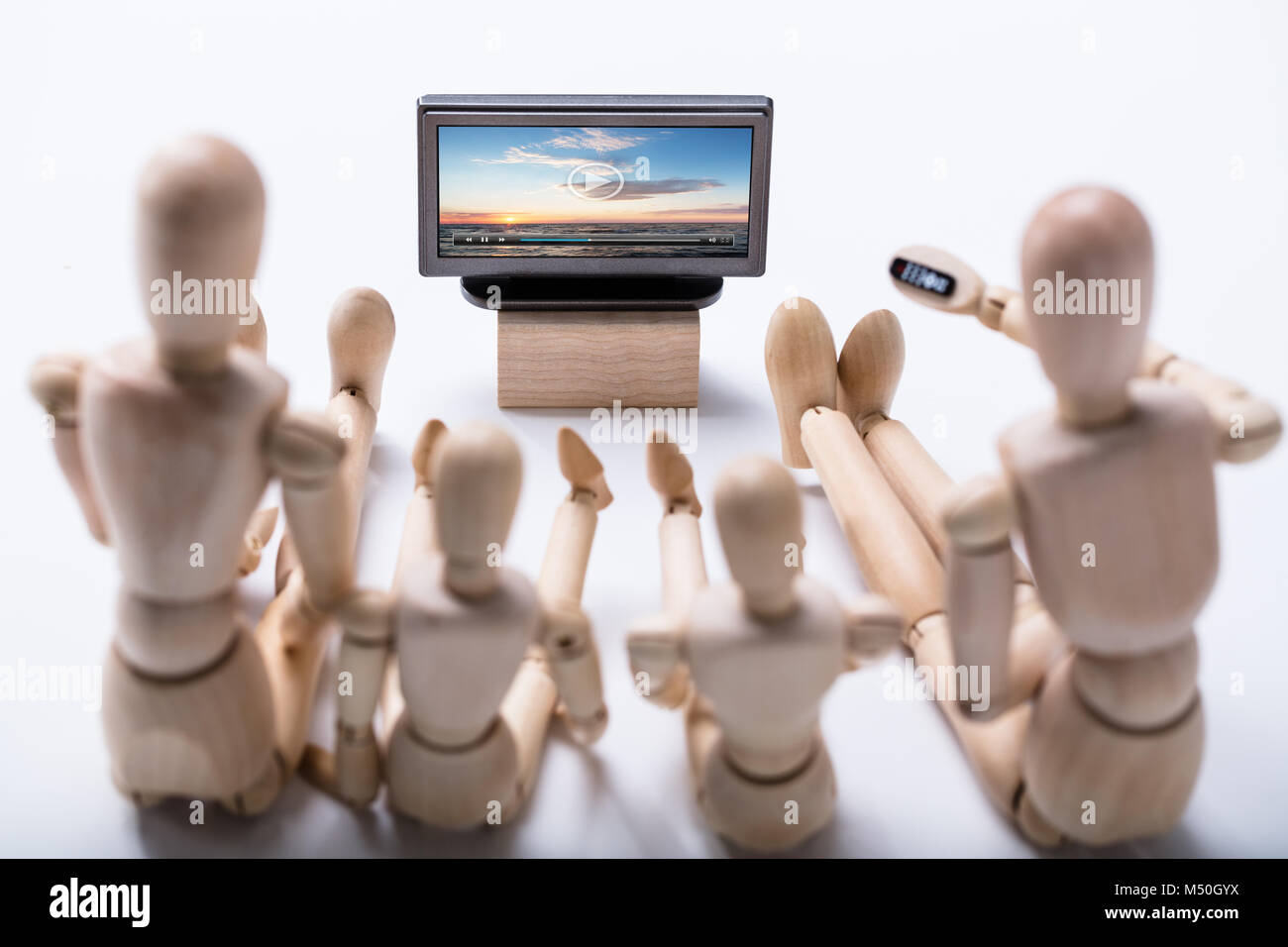 High Angle View Of Wooden Dummy Family Sitting On Floor Watching Video ...