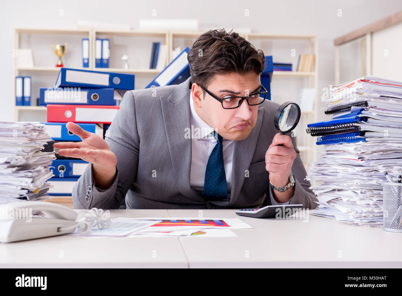 Male businessman with magnifying glass in office Stock Photo - Alamy