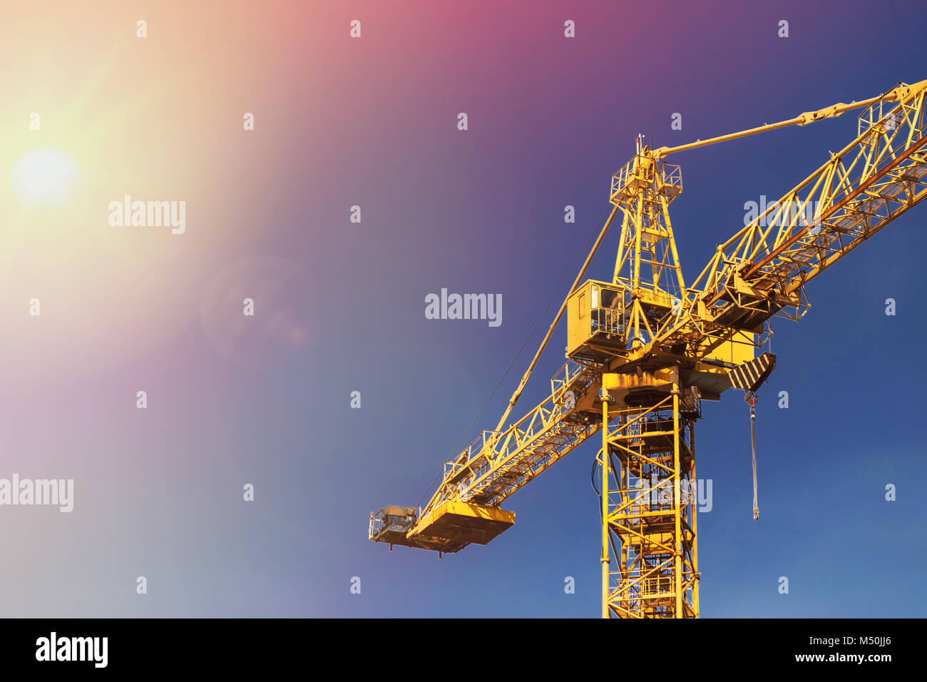 Construction crane tower in sun light on background of blue sky. Crane ...
